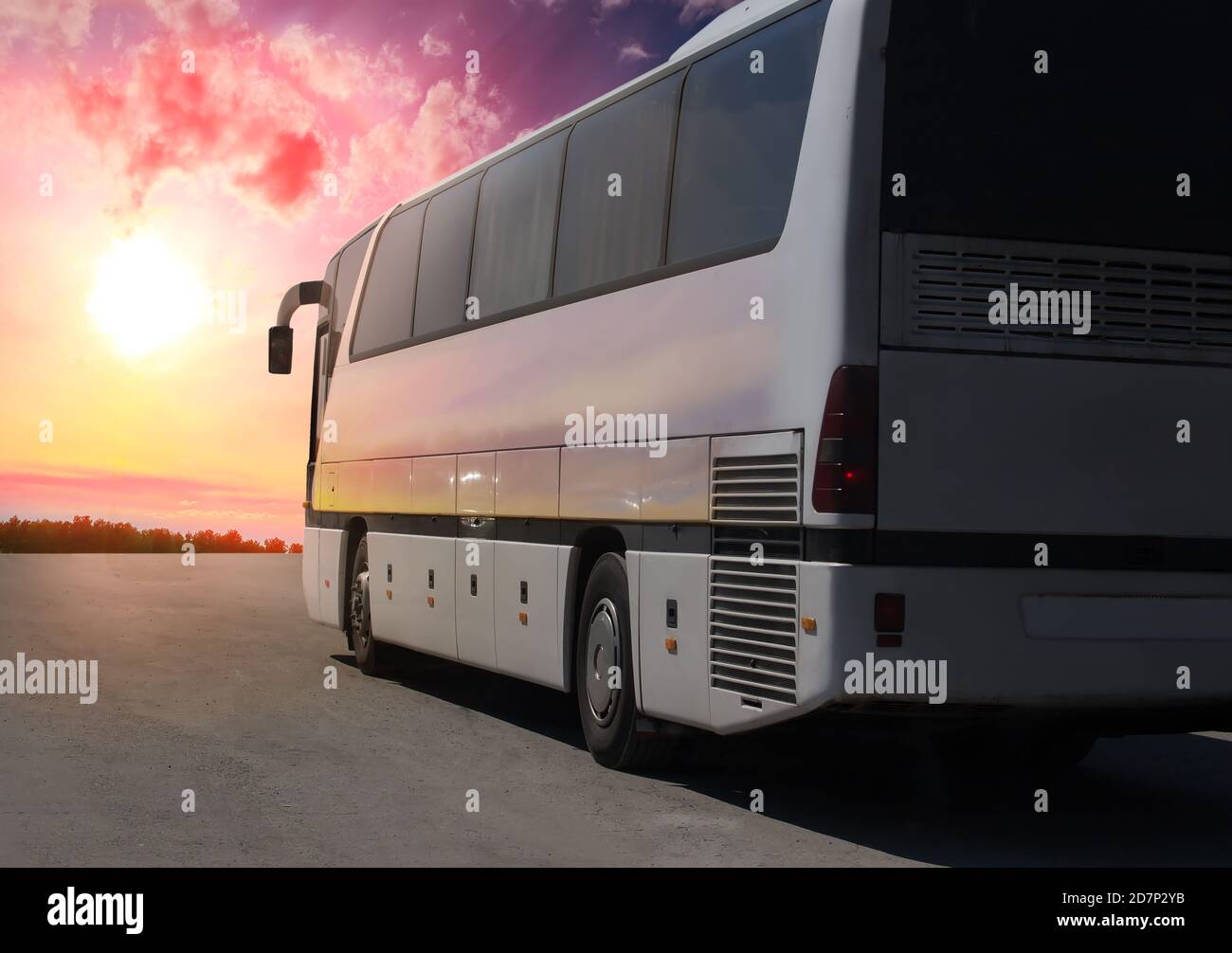 tourist bus moving along the highway under the sunny sky at sunset ...