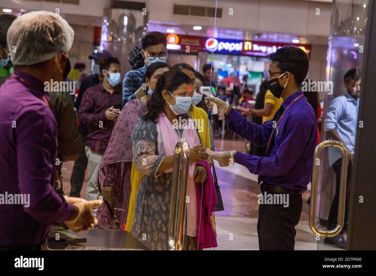October 23, 2020: A staff checks temperature of a woman while entering ...