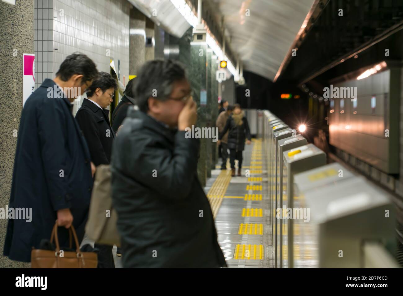 Commuters wait to get on the Toei Oedo Line at Morishita Station at ...