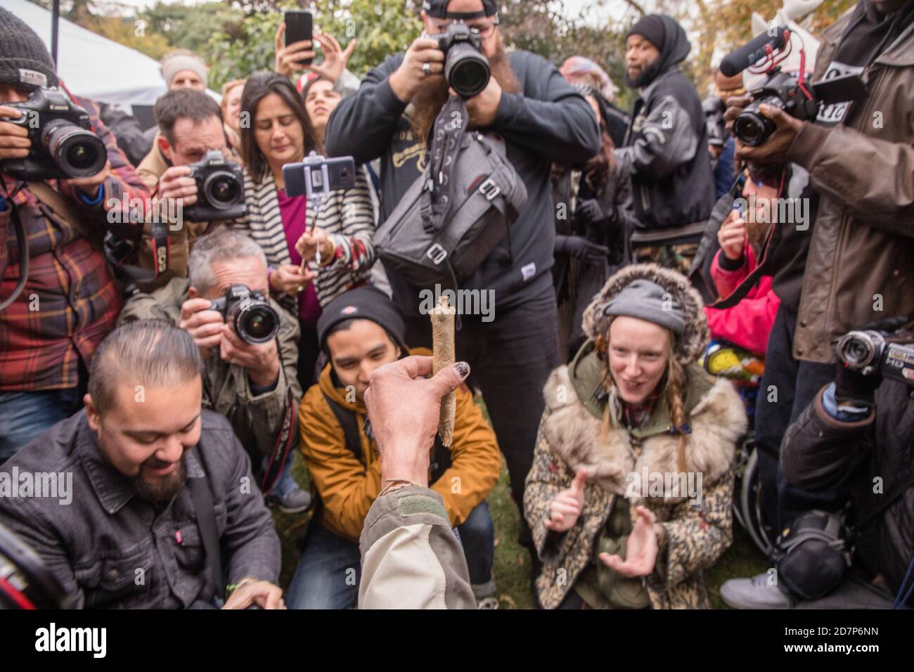 A man holding up a big joint while people surround him during the ...