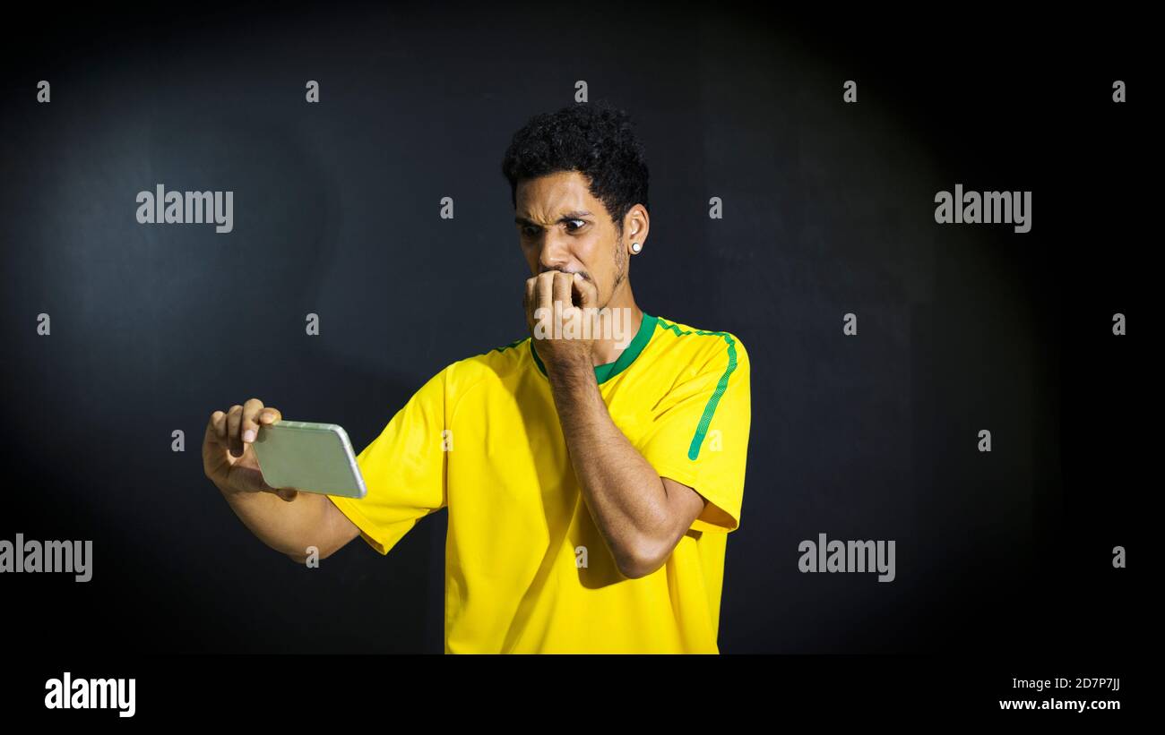Male athlete or fan in yellow uniform looking cell phone on black ...