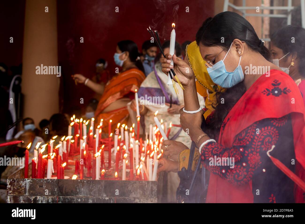 A Hindu devotee wearing a face mask is seen holding a lit Diya (Soil ...