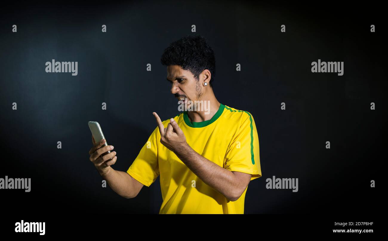 Male athlete or fan in yellow uniform looking cell phone on black ...