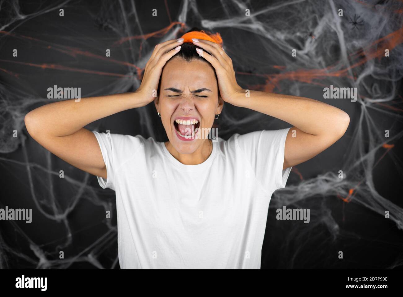 Young beautiful woman over black background with cobwebs and spiders ...