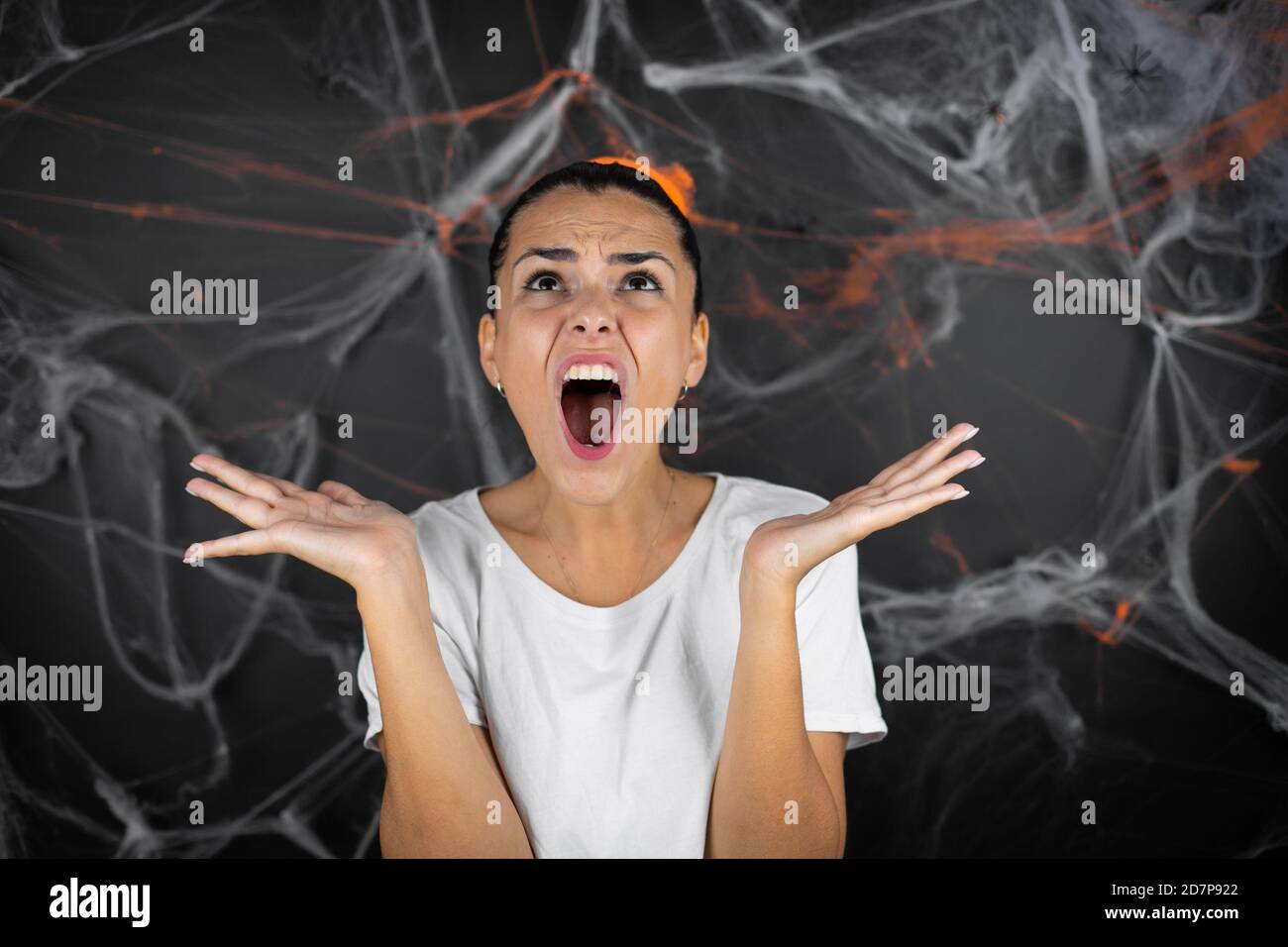 Young beautiful woman over black background with cobwebs and spiders ...