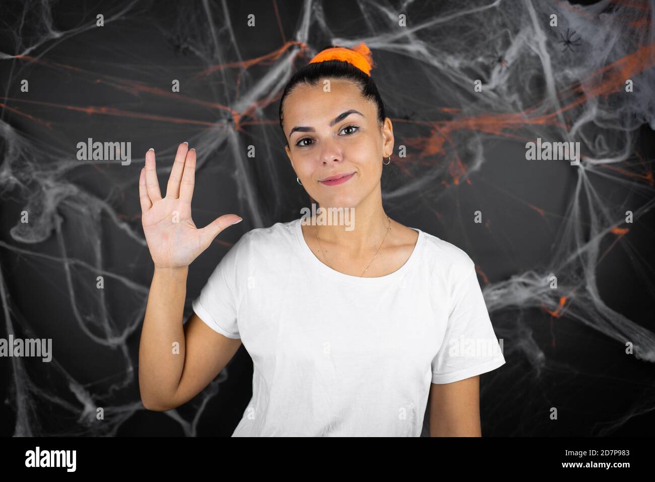 Young beautiful woman over black background with cobwebs and spiders ...
