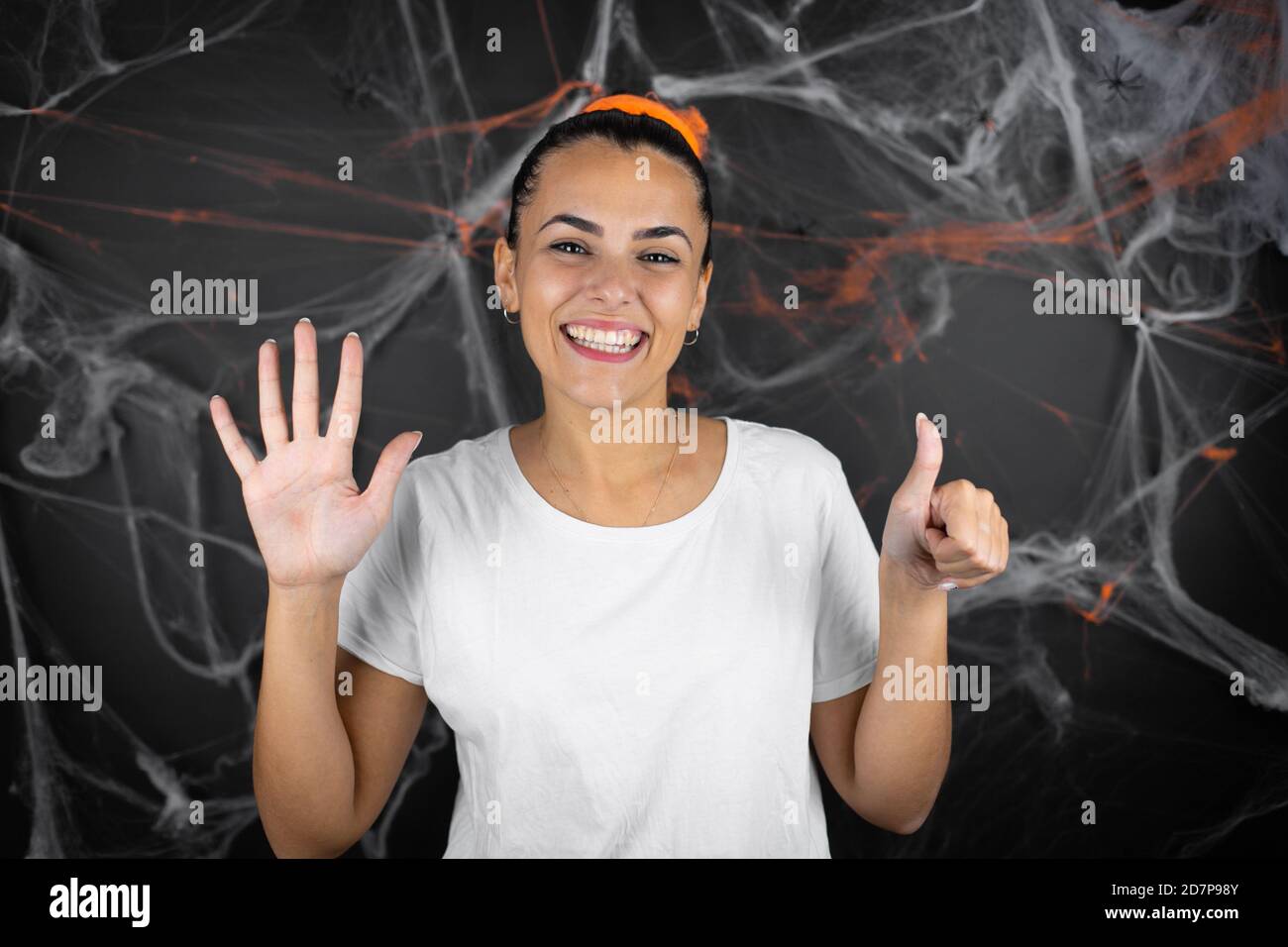 Young beautiful woman over black background with cobwebs and spiders ...
