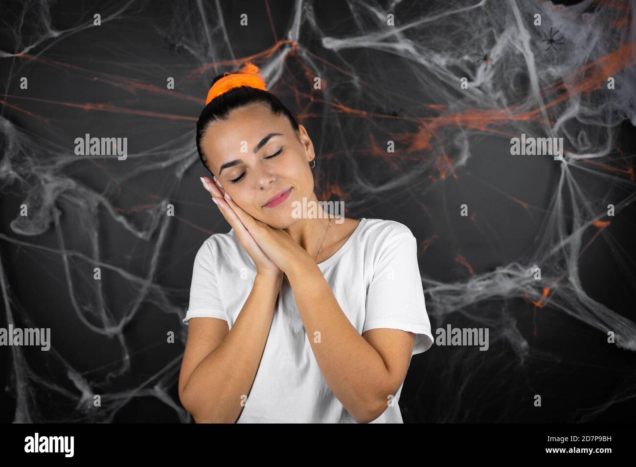Young beautiful woman over black background with cobwebs and spiders ...