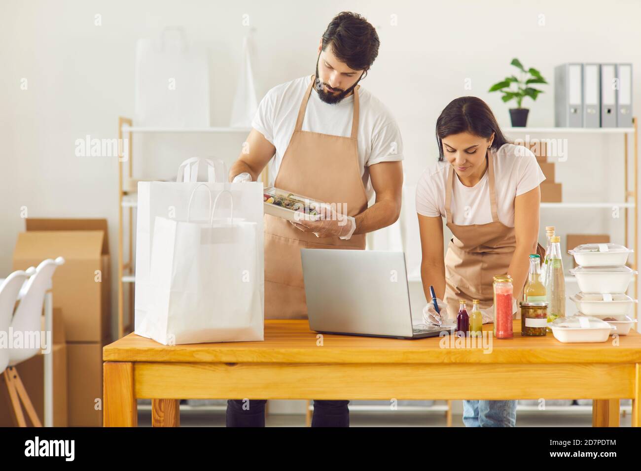 Employees of a healthy food restaurant record data and pack food ...