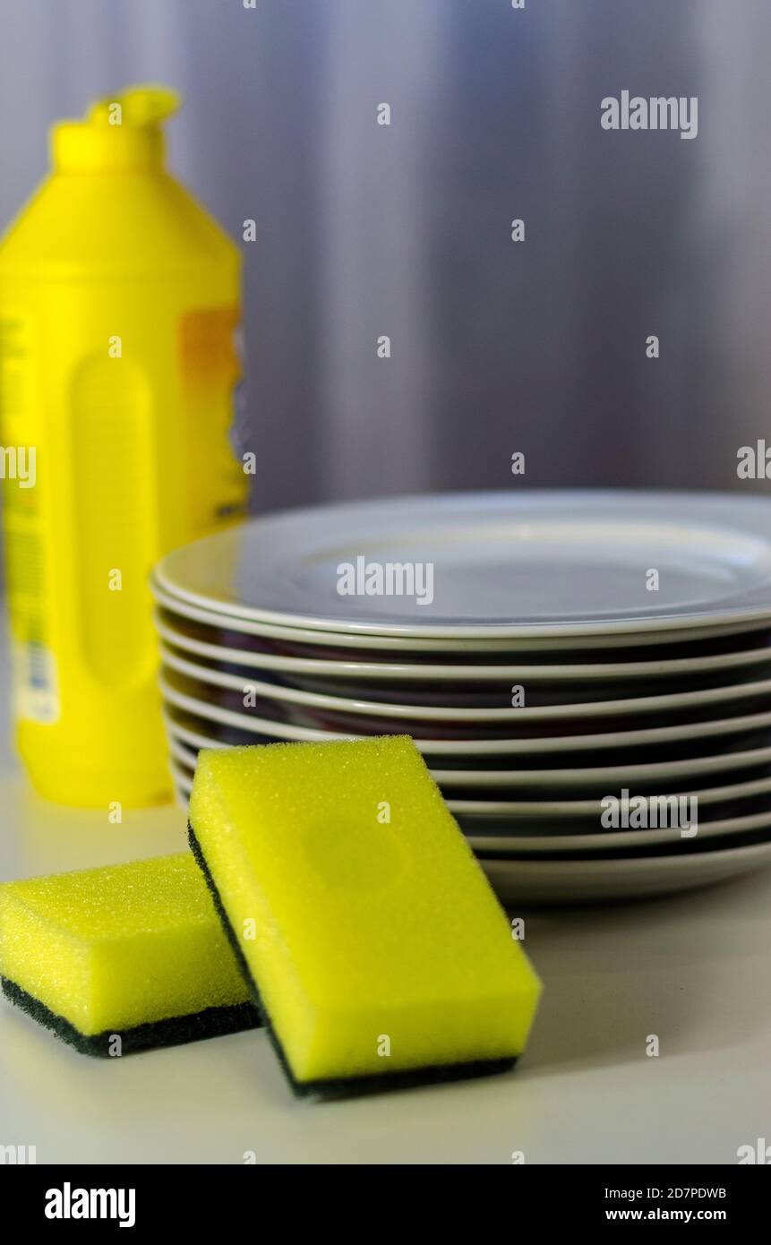Bottle of dishwashing liquid and stack of utensils isolated on white ...