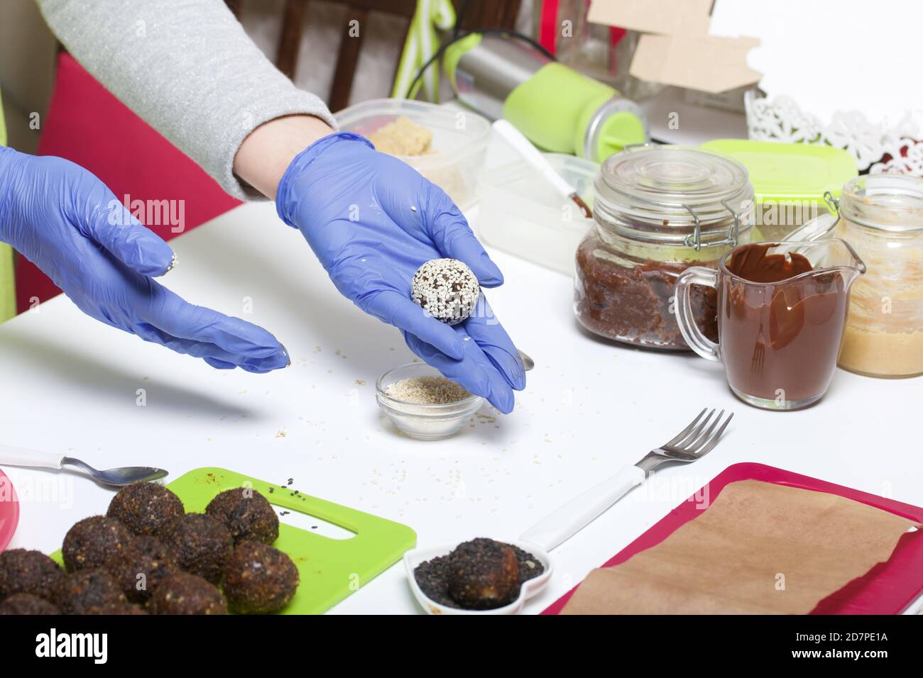 A woman in rubber gloves makes candies from dried fruits and nuts. Some ...