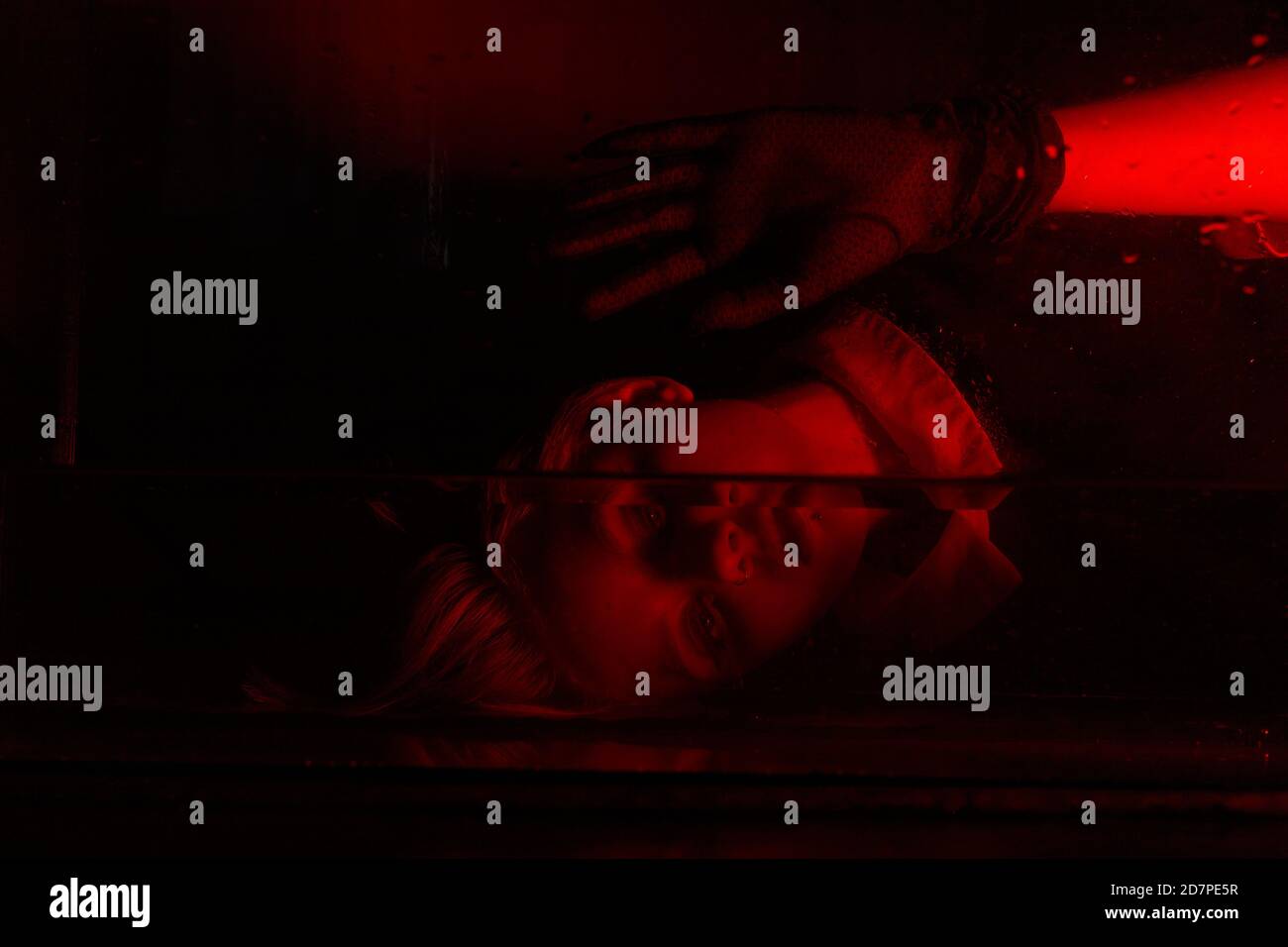 Horrible portrait of a young girl in a horror room with a red light ...