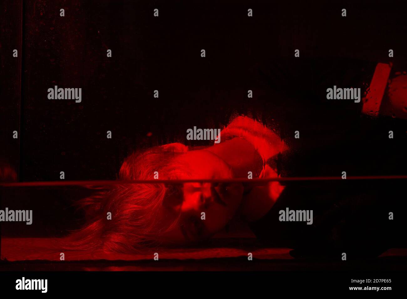 Horrible portrait of a young girl in a horror room with a red light ...