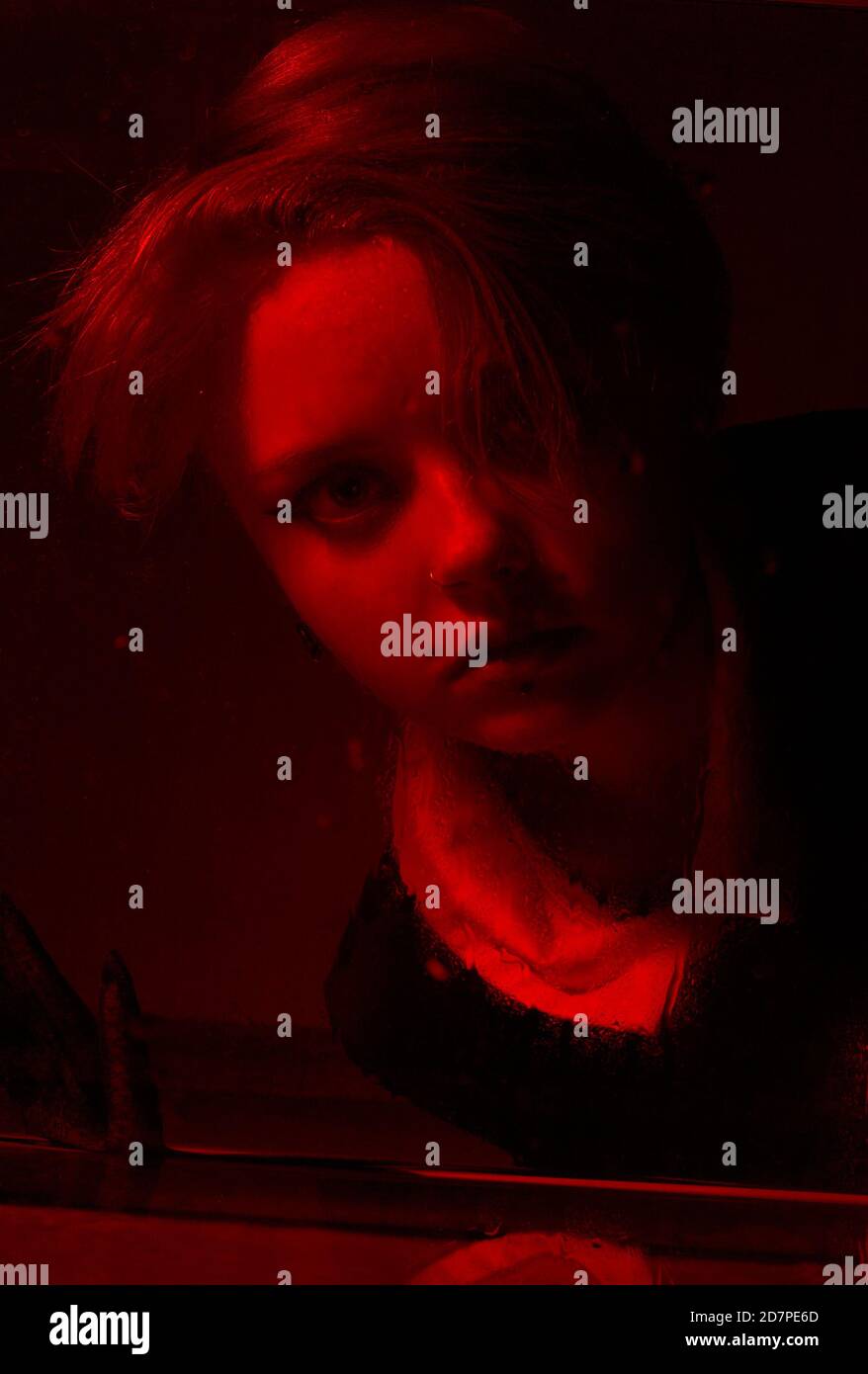 Horrible portrait of a young girl in a horror room with a red light ...