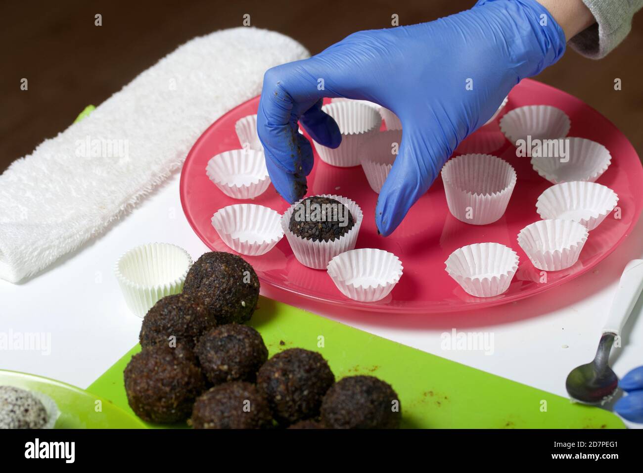 A woman in rubber gloves makes candies from dried fruits and nuts. Some ...