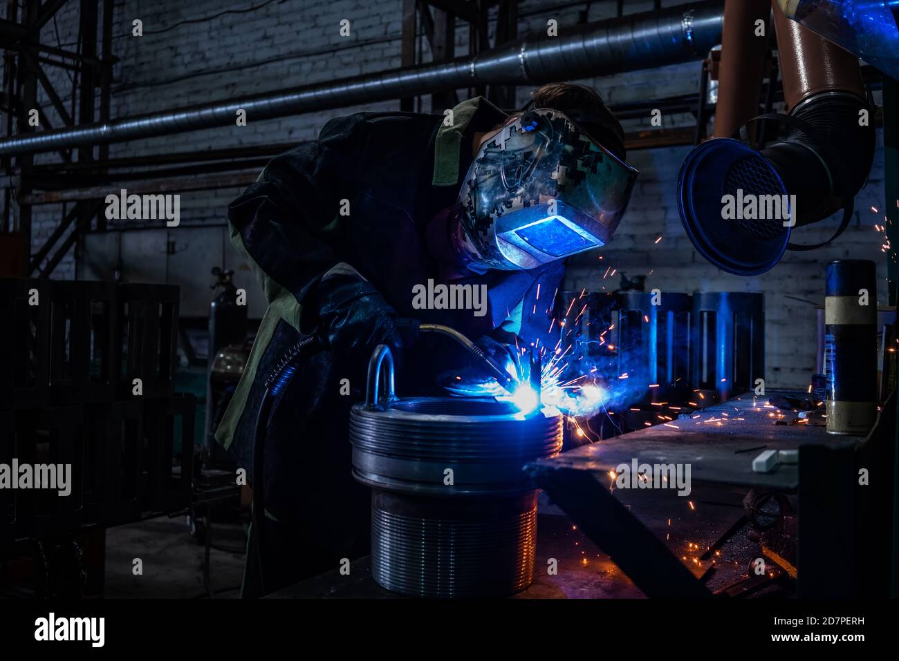 Side view of welder in protective helmet welding metal detail with ...