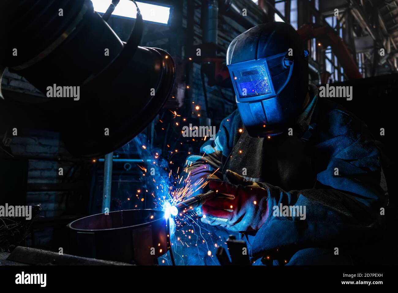 Side view of welder in protective helmet welding metal detail with ...