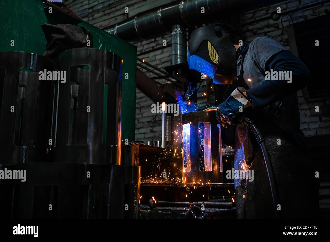 Side view of welder in protective helmet welding metal detail with ...