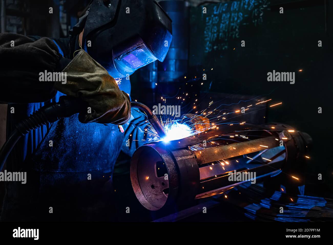 Side view of welder in protective helmet welding metal detail with ...