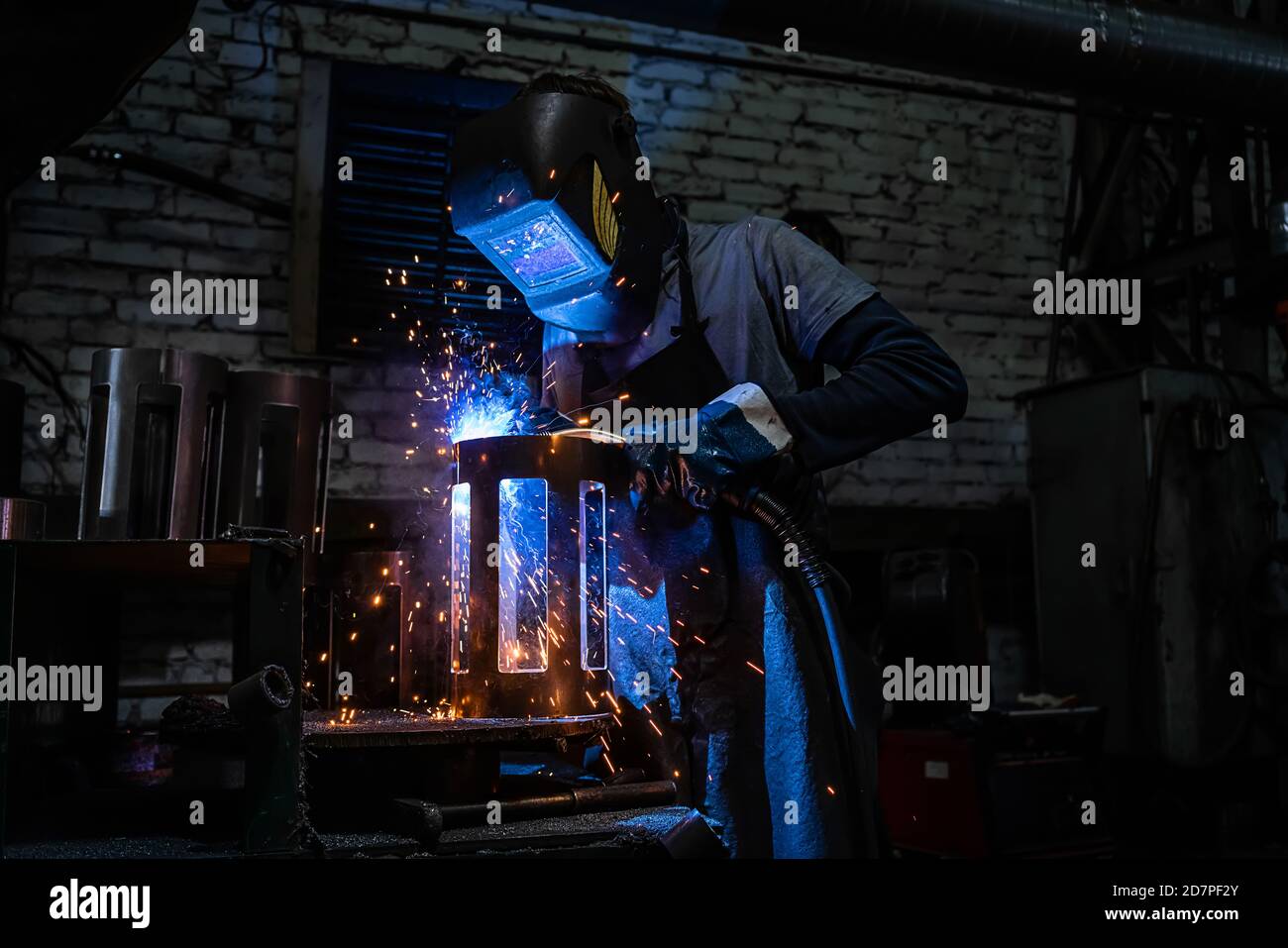 Side view of welder in protective helmet welding metal detail with ...