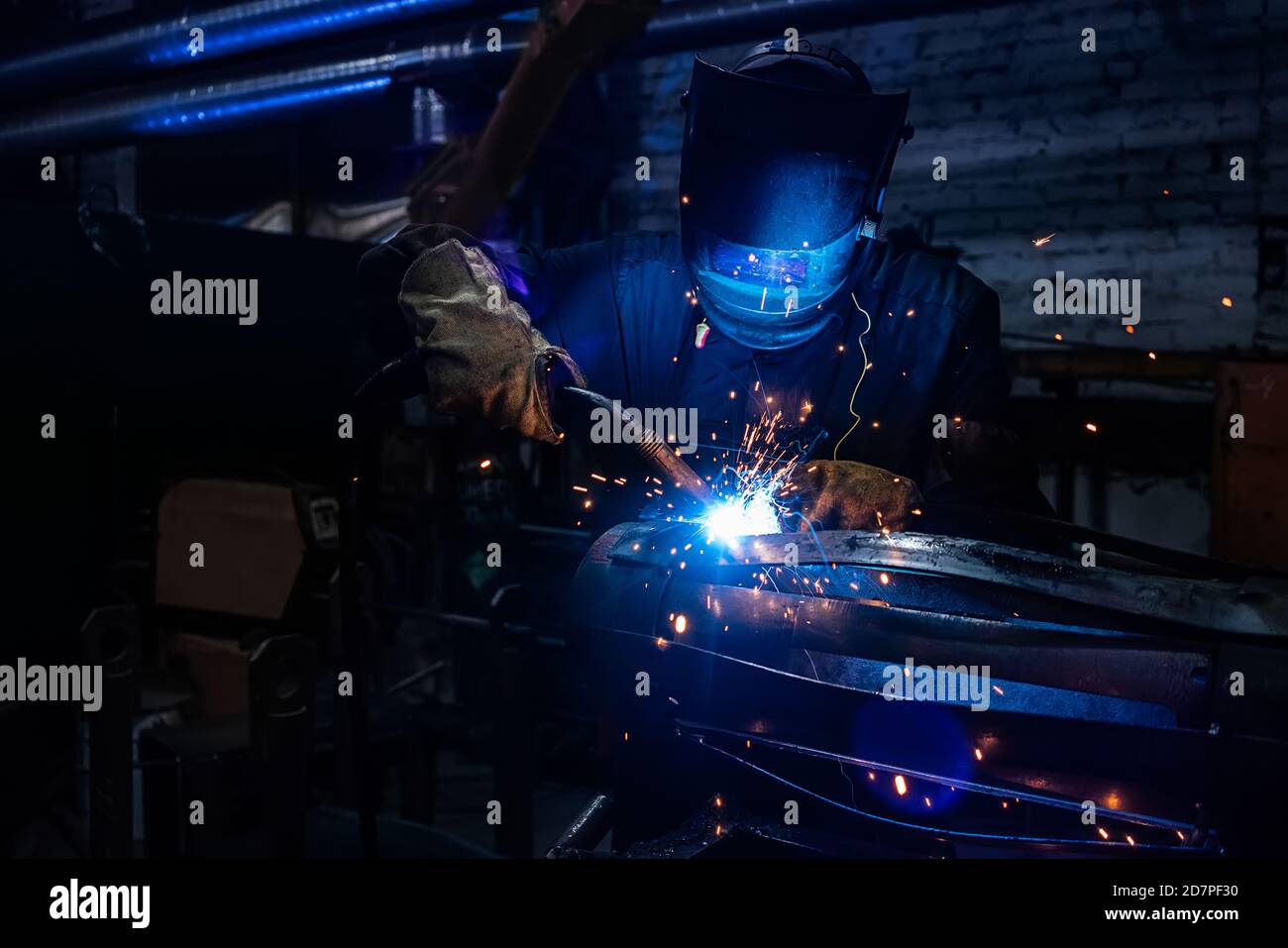 Side view of welder in protective helmet welding metal detail with ...