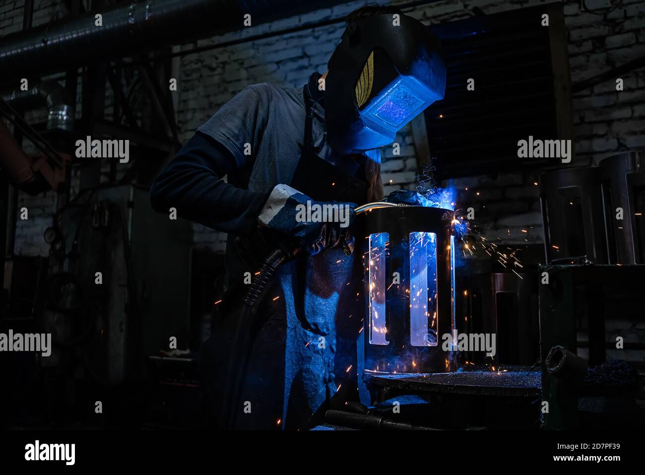 Side view of welder in protective helmet welding metal detail with ...