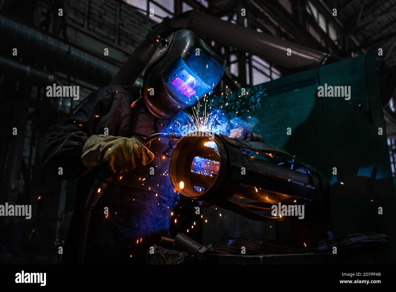Side view of welder in protective helmet welding metal detail with ...