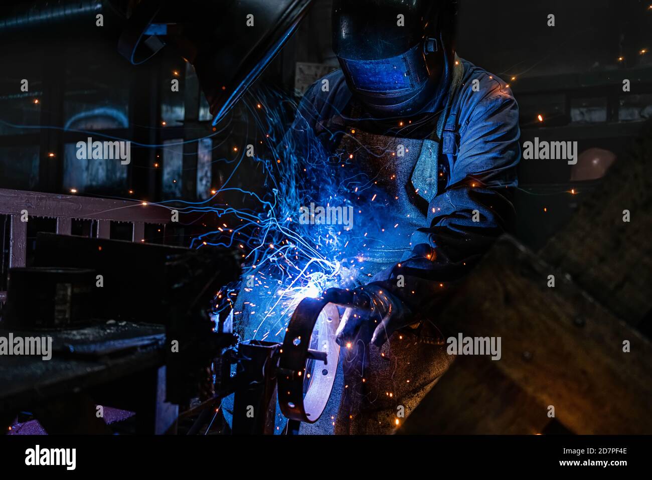 Side view of welder in protective helmet welding metal detail with ...