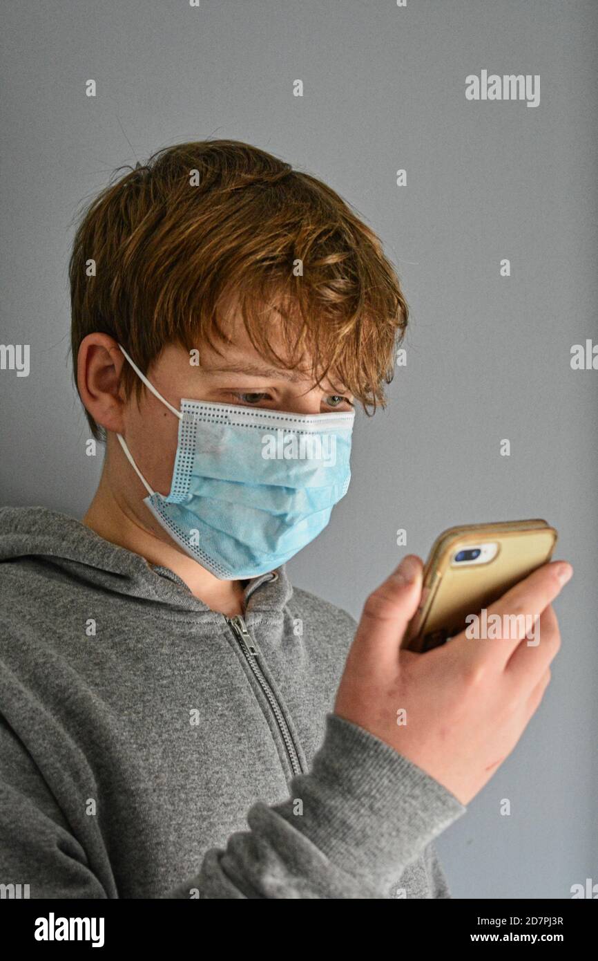 Teenage boy using his smartphone in surgical face mask Stock Photo - Alamy