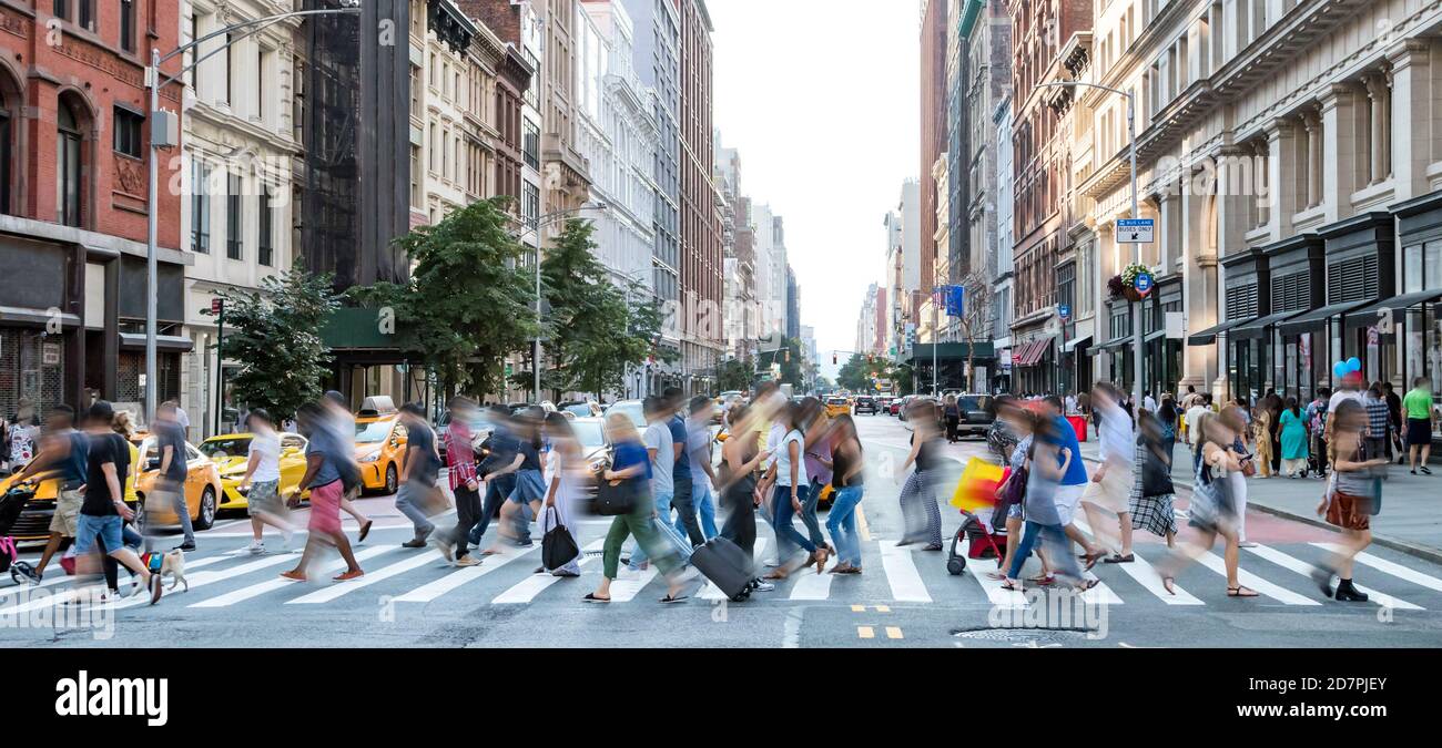 Busy street scene in New York City with groups of people walking across ...