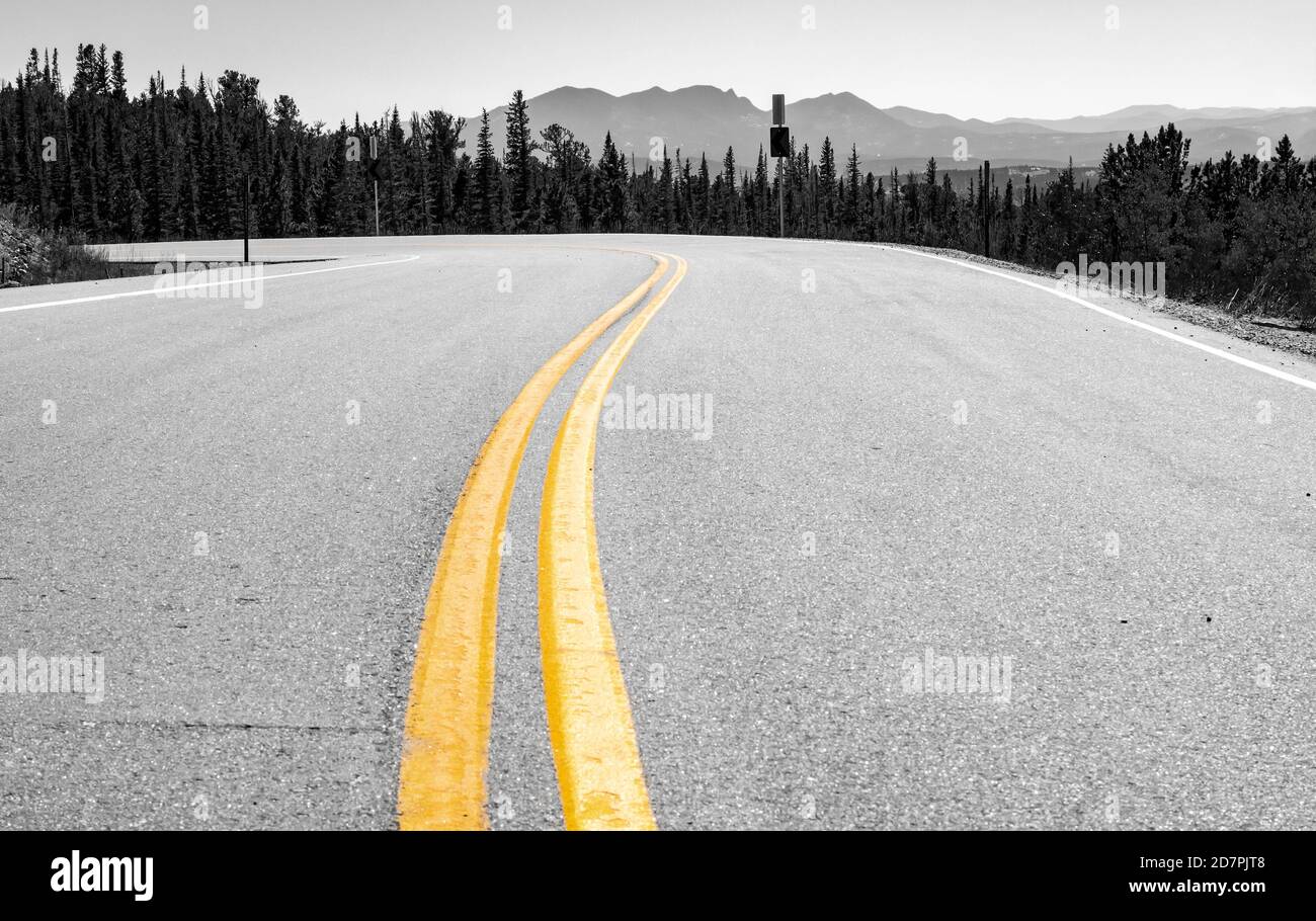 Yellow divider lines on an empty highway as it curves through a ...