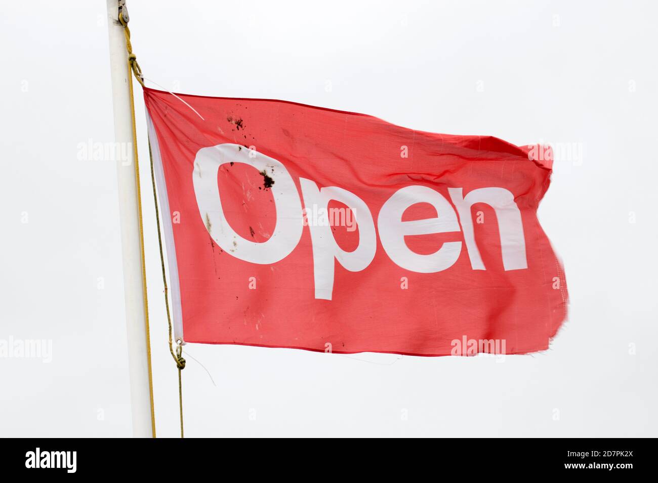 Red flag with the word open, flying in the wind at the seaside town of ...