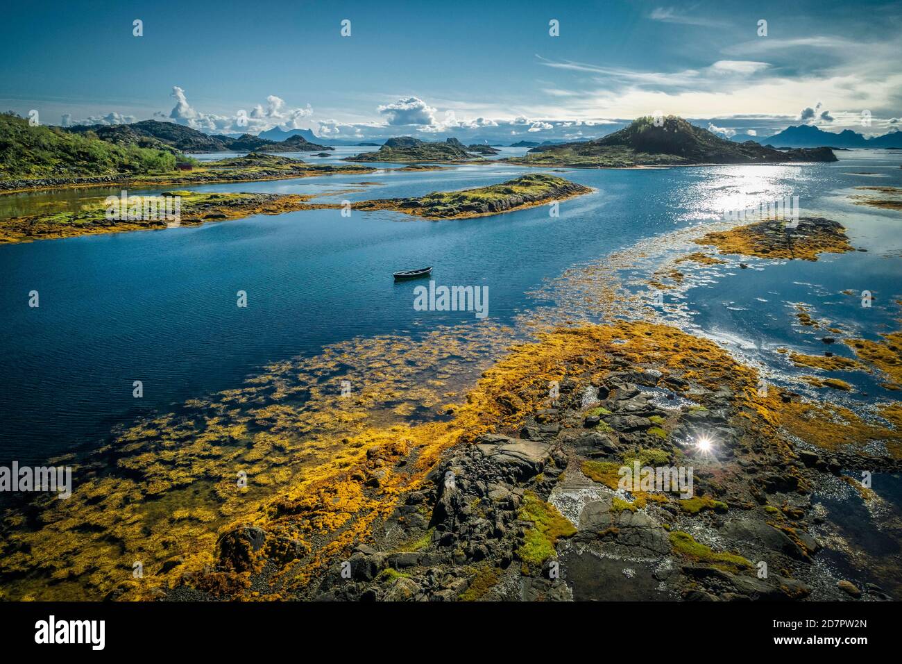 Fjord landscape with small rock islands at low tide with yellow seaweed ...