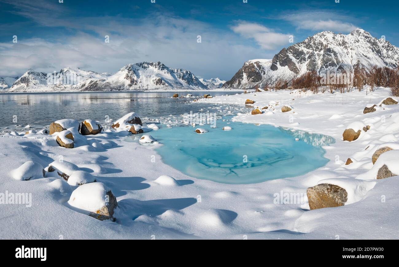 Turquoise lagoon with snow surface and ice floes, behind it snow ...