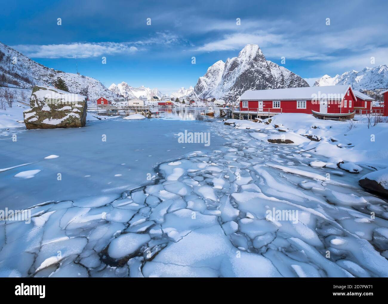 Ice floes in the frozen fjord, behind red wooden houses and winter ...