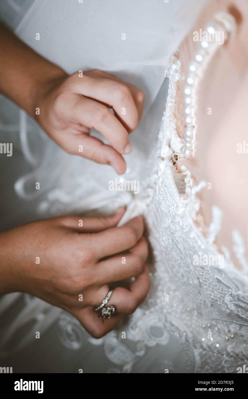Vertical shot of bridesmaid hands helping bride to dress up Stock Photo ...