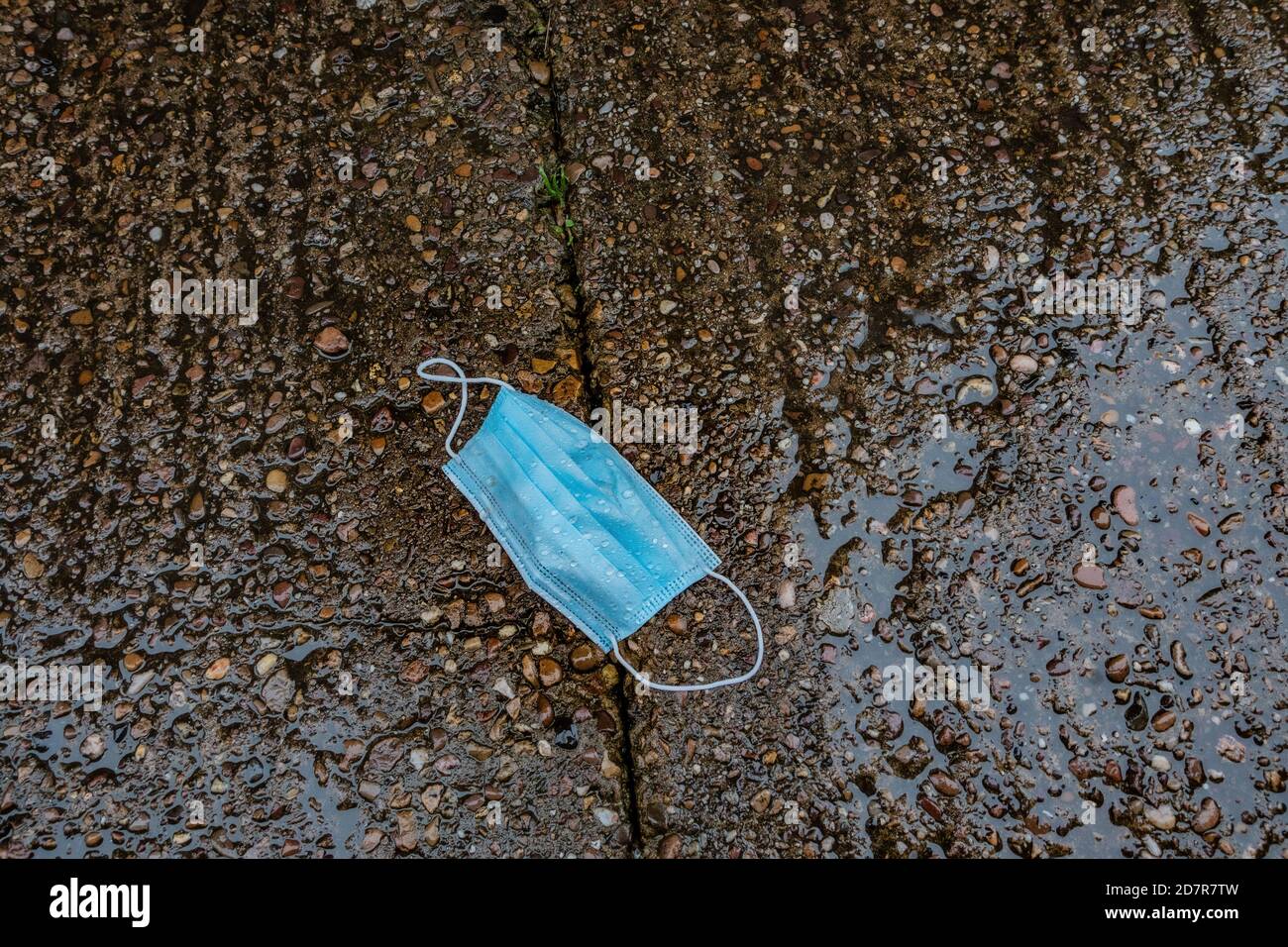 Discarded face mask dropped on the wet floor Stock Photo - Alamy