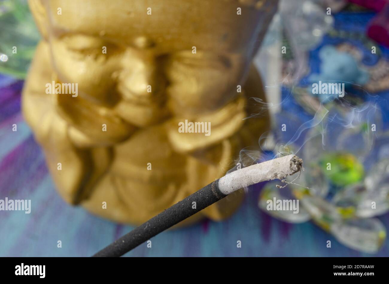 Closeup shot of smoking incense stick with buddha statue in the ...