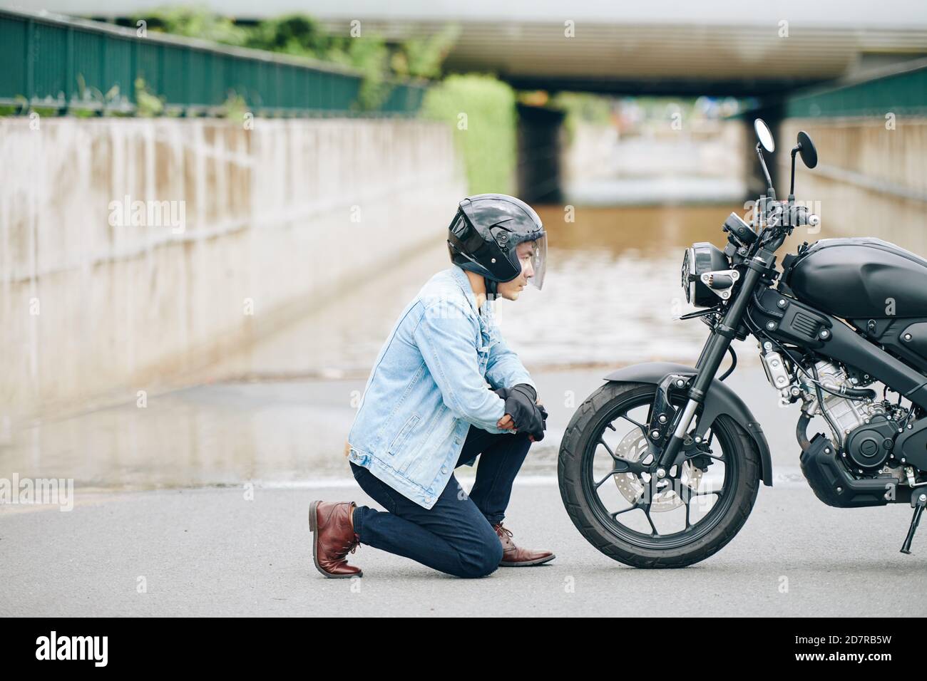Motorcyclist looking at headlight Stock Photo - Alamy