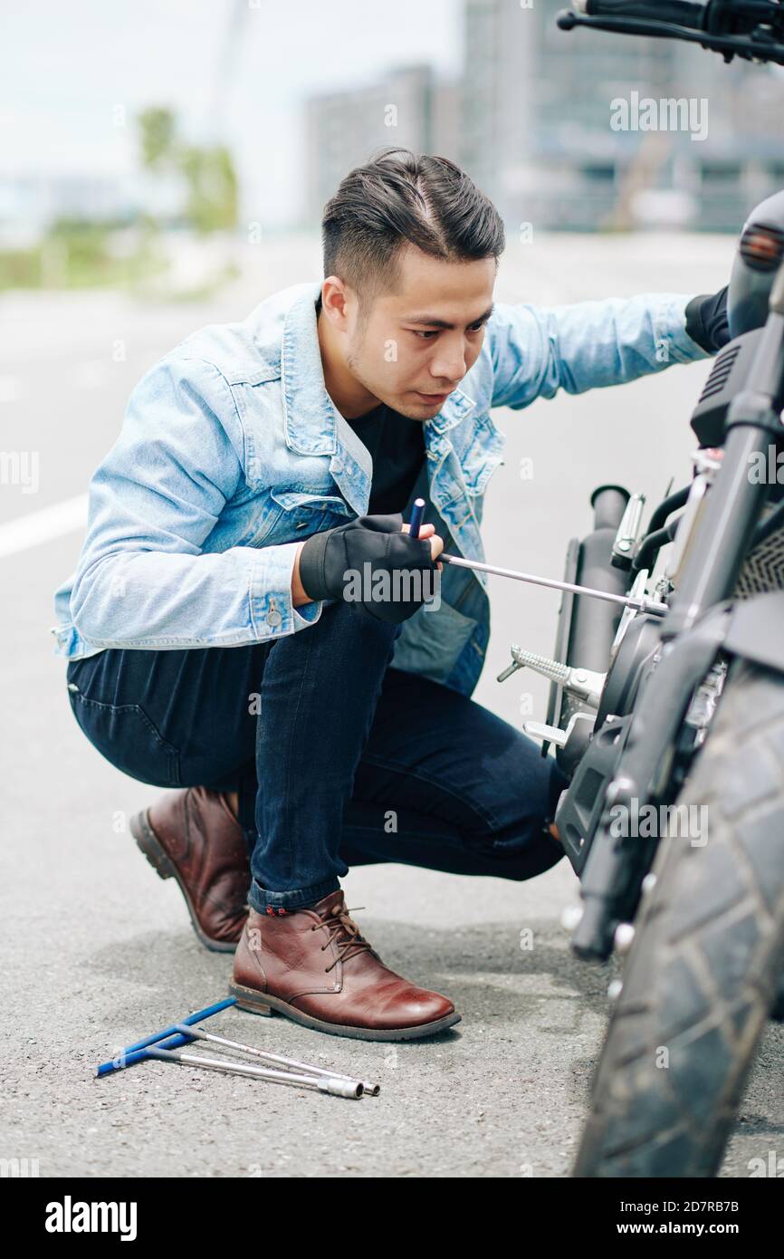 Man fixing his broken motorcycle Stock Photo - Alamy