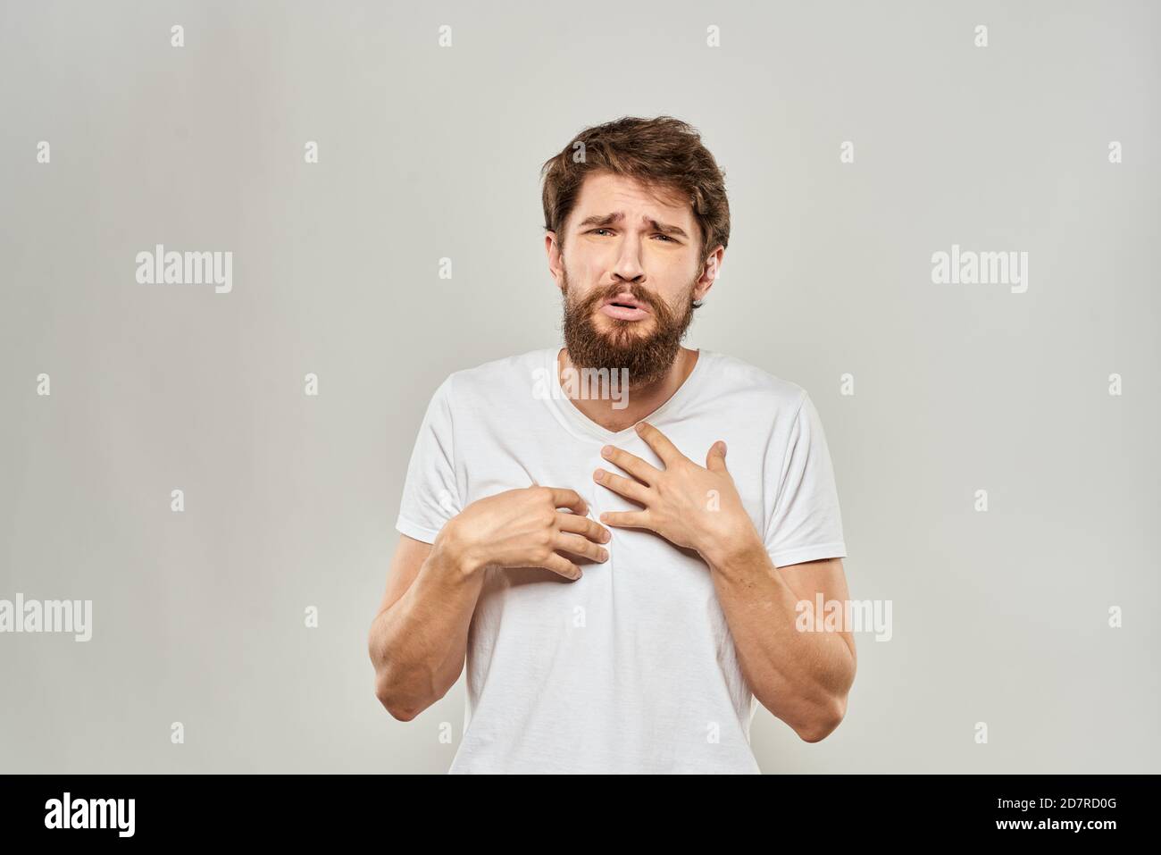 A man in a white t-shirt with a beard emotions displeased facial ...