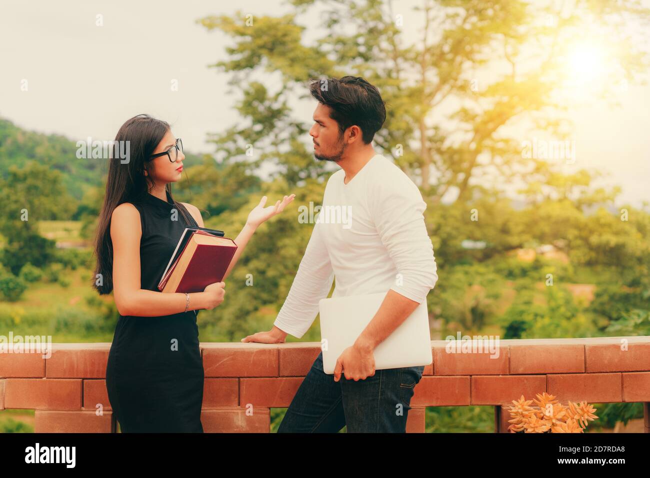 Two students with books and laptop talking in the university. College ...