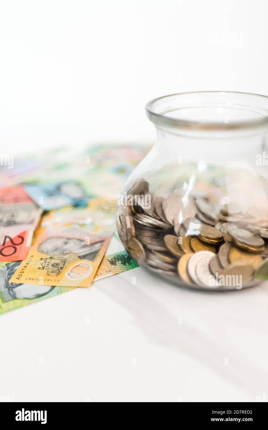 Vertical shot of a jar with coins and Australian dollar banknotes on ...