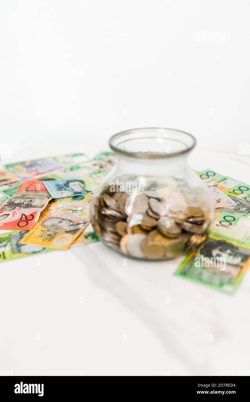 Vertical shot of a jar with coins and Australian dollar banknotes on ...