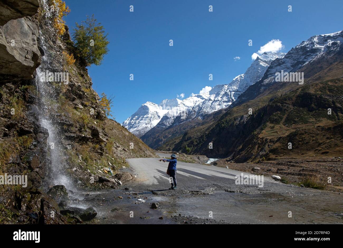 A pretty lady enjoying a high altitude road side water fall from a high ...