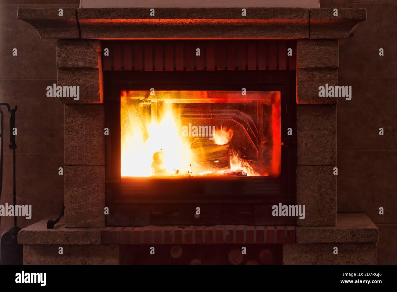 In the fireplace burning logs. View through heat resistant glass door ...
