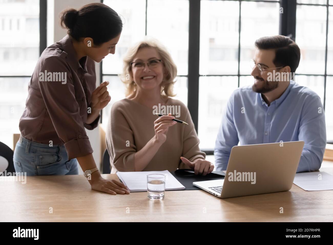 Smiling diverse colleagues have fun collaborating at meeting Stock ...