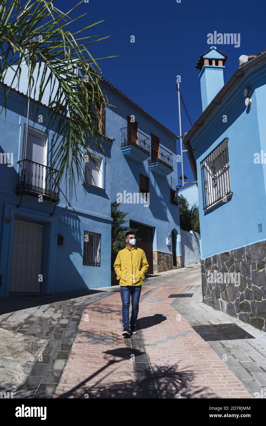 Vertical shot of a young man walking wearing a sanitary mask - concept ...