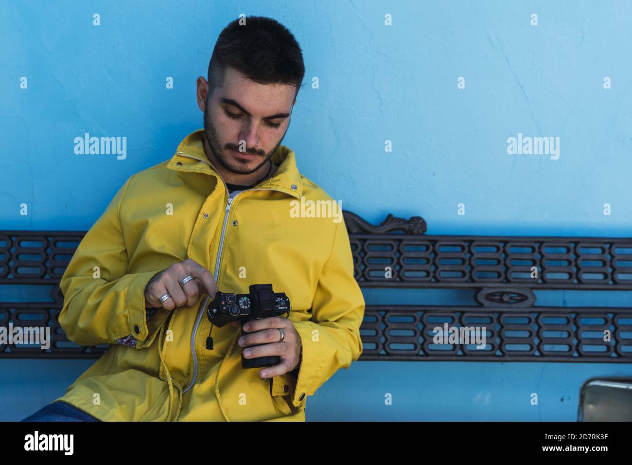 Closeup shot of a young man holding a camera sitting on a bench Stock ...