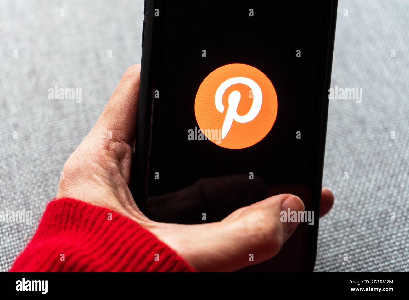 Young woman holding a smartphone with Pinterest app on screen. IPhone ...